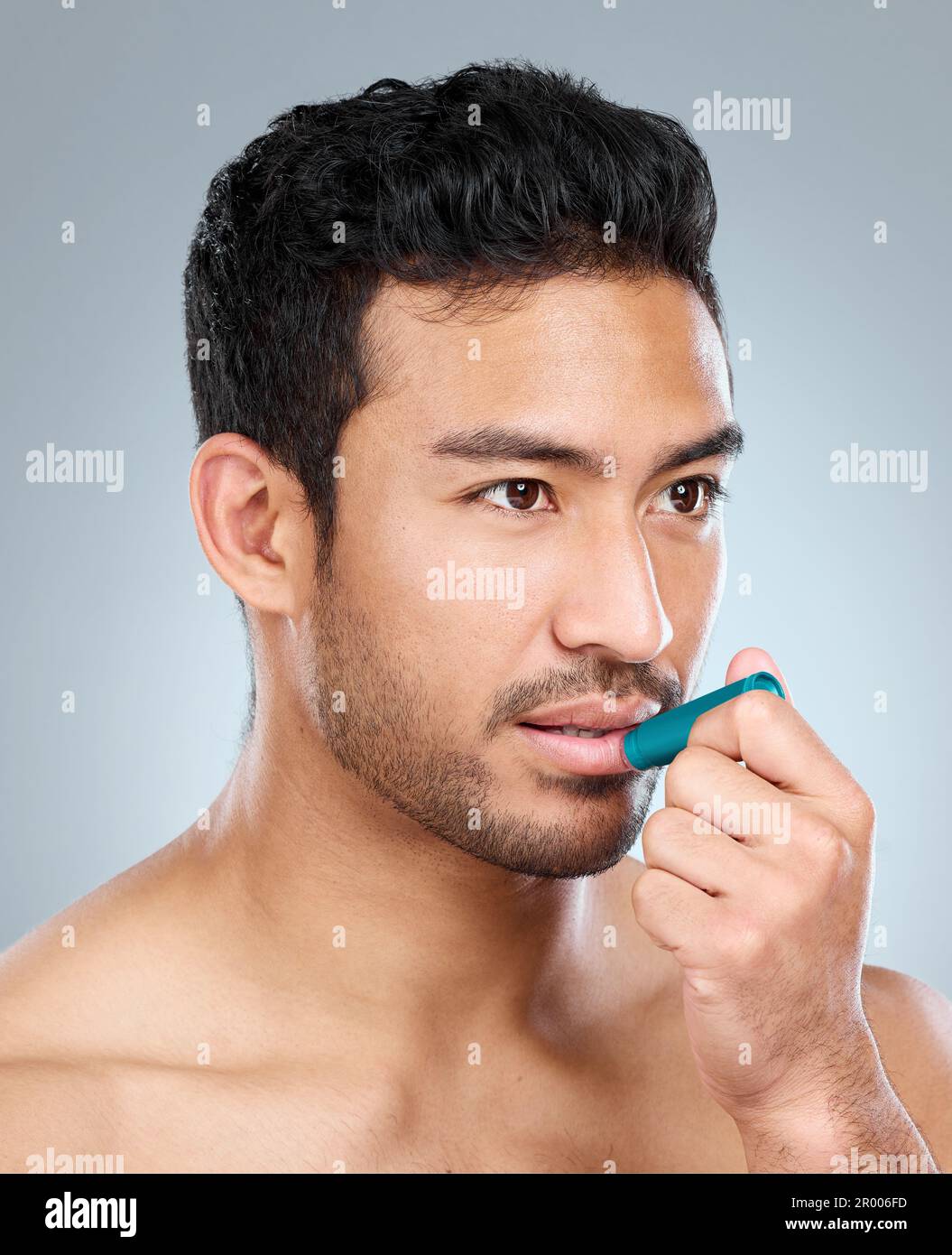 Nourish and moisturise your lips. a man applying lip balm while ...