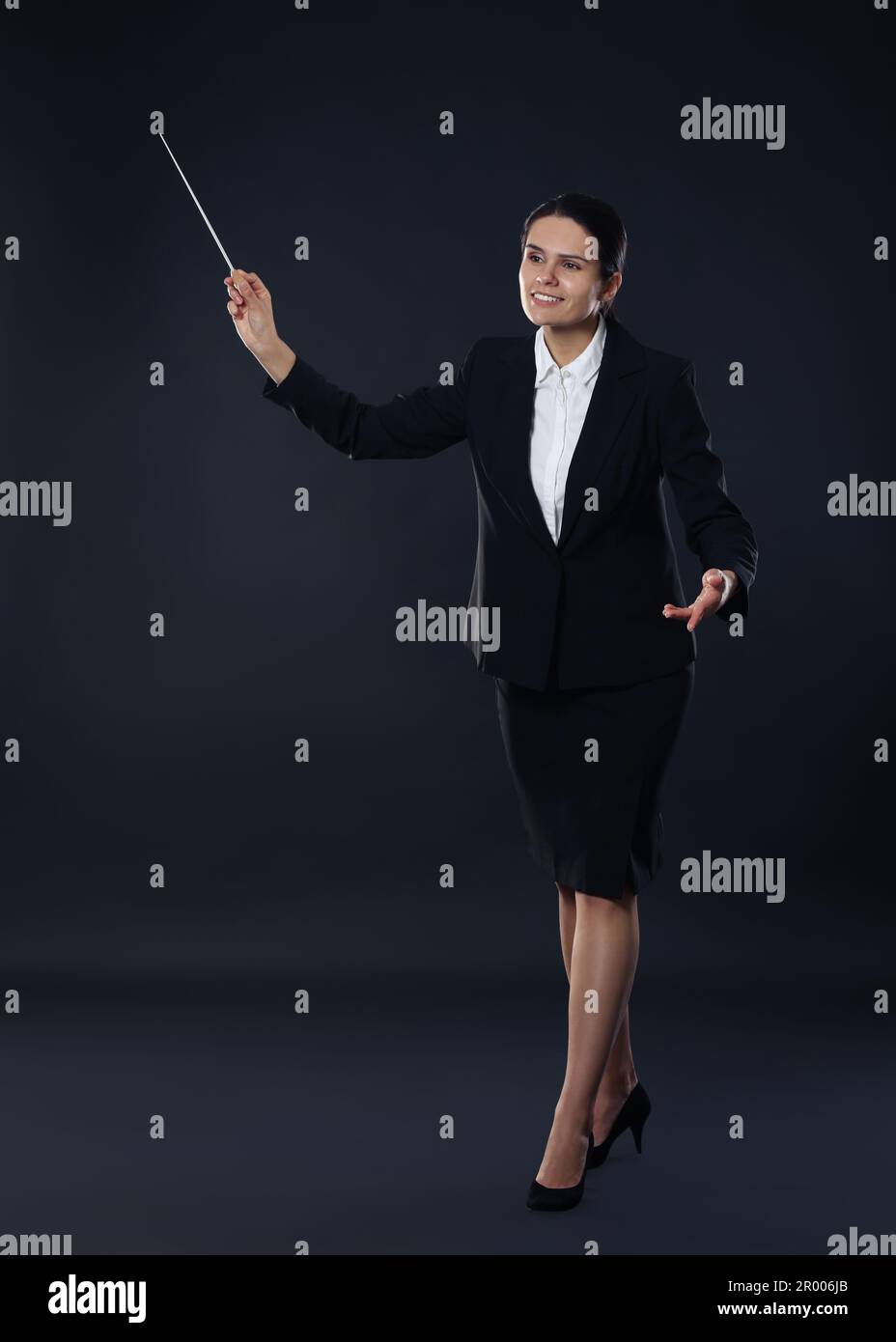 Happy young conductor with baton on dark background Stock Photo - Alamy