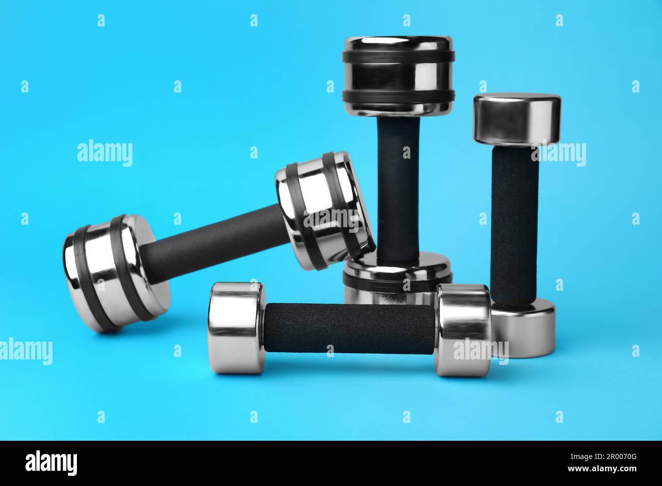 Many stylish dumbbells on light blue background Stock Photo - Alamy