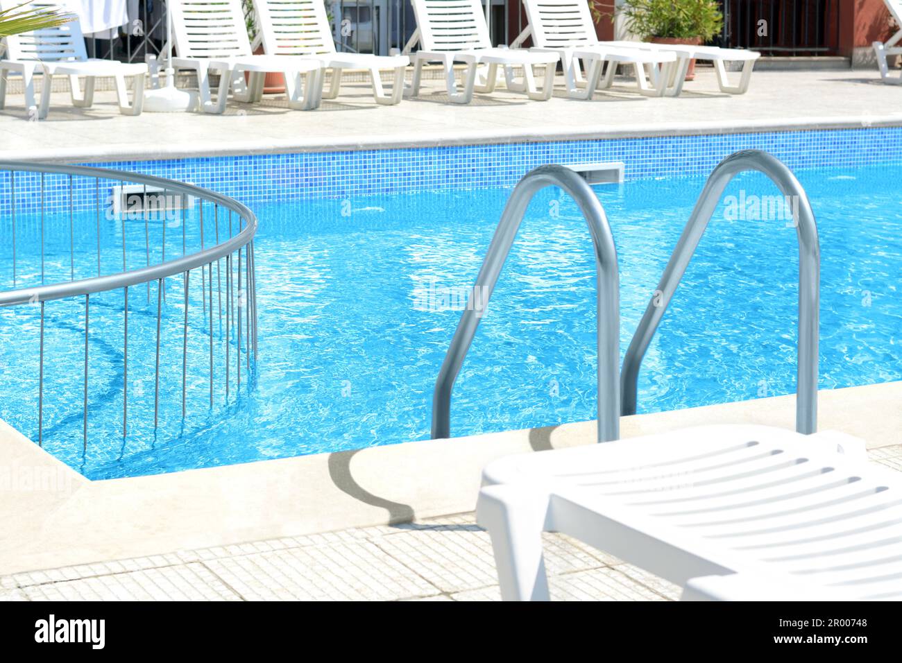 Outdoor swimming pool and loungers at resort sunny day Stock Photo - Alamy