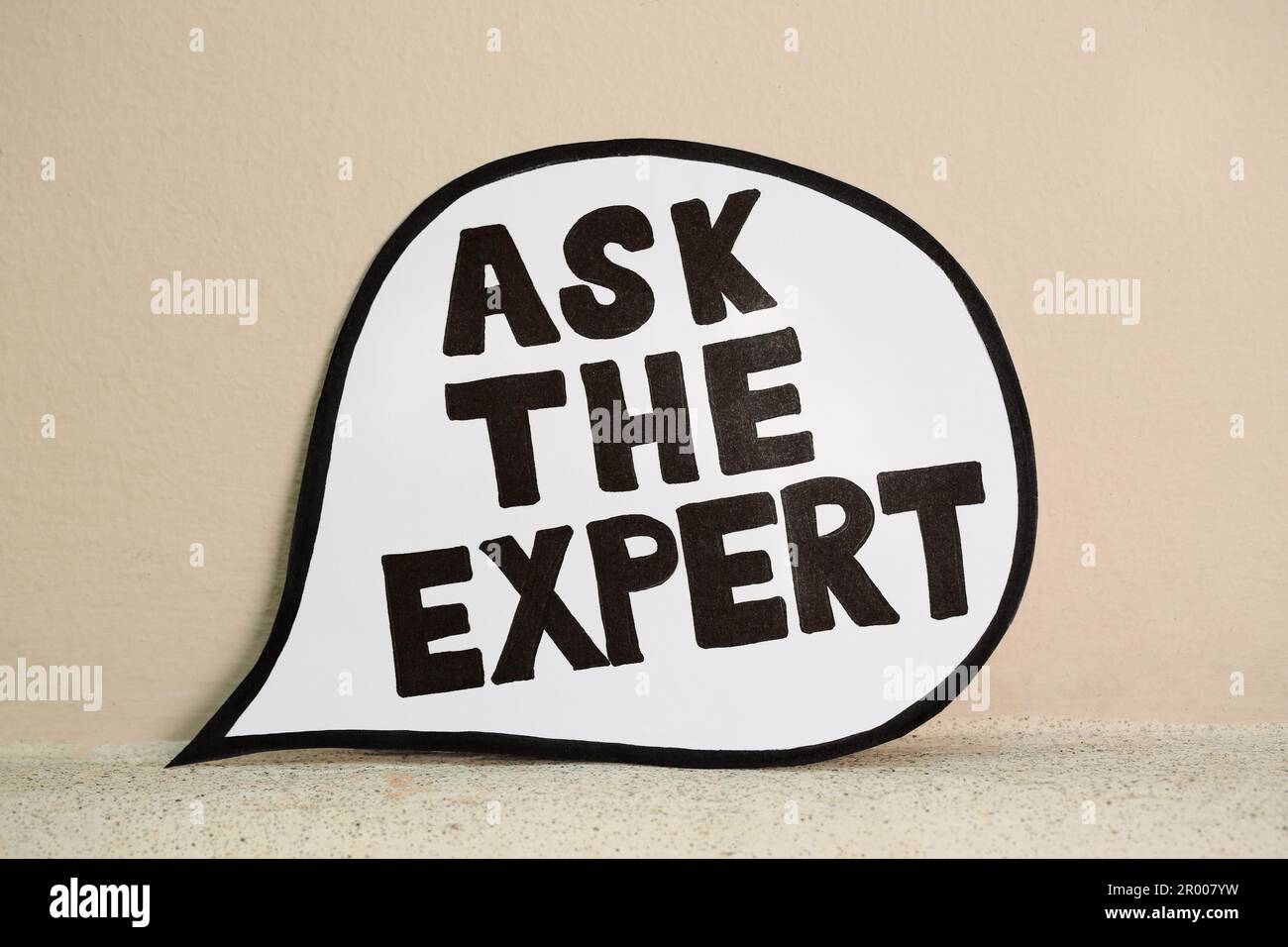 Paper message bubble with phrase Ask The Expert near beige wall Stock Photo - Alamy