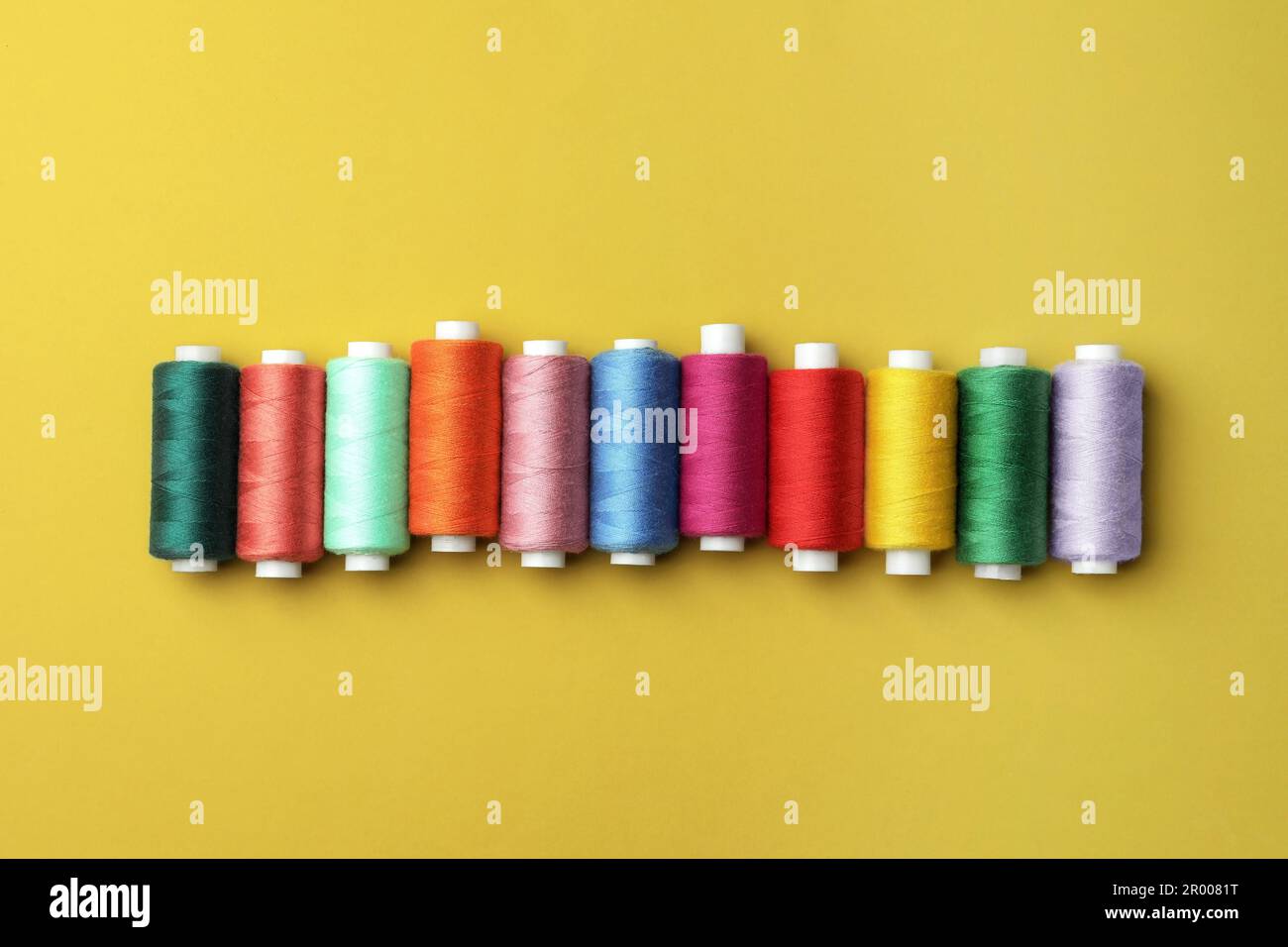 Set of colorful sewing threads on yellow background, flat lay Stock ...