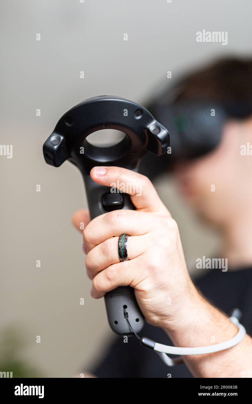 Focus on hand holding VR wand remote controller with young man playing ...