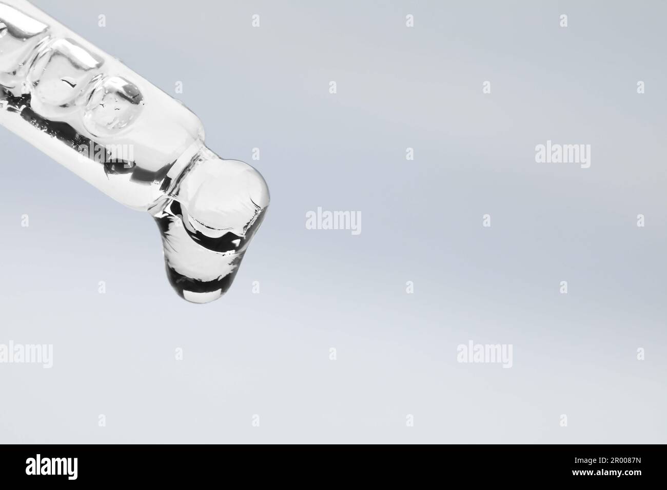 Dripping face serum from pipette on white background, closeup. Space ...