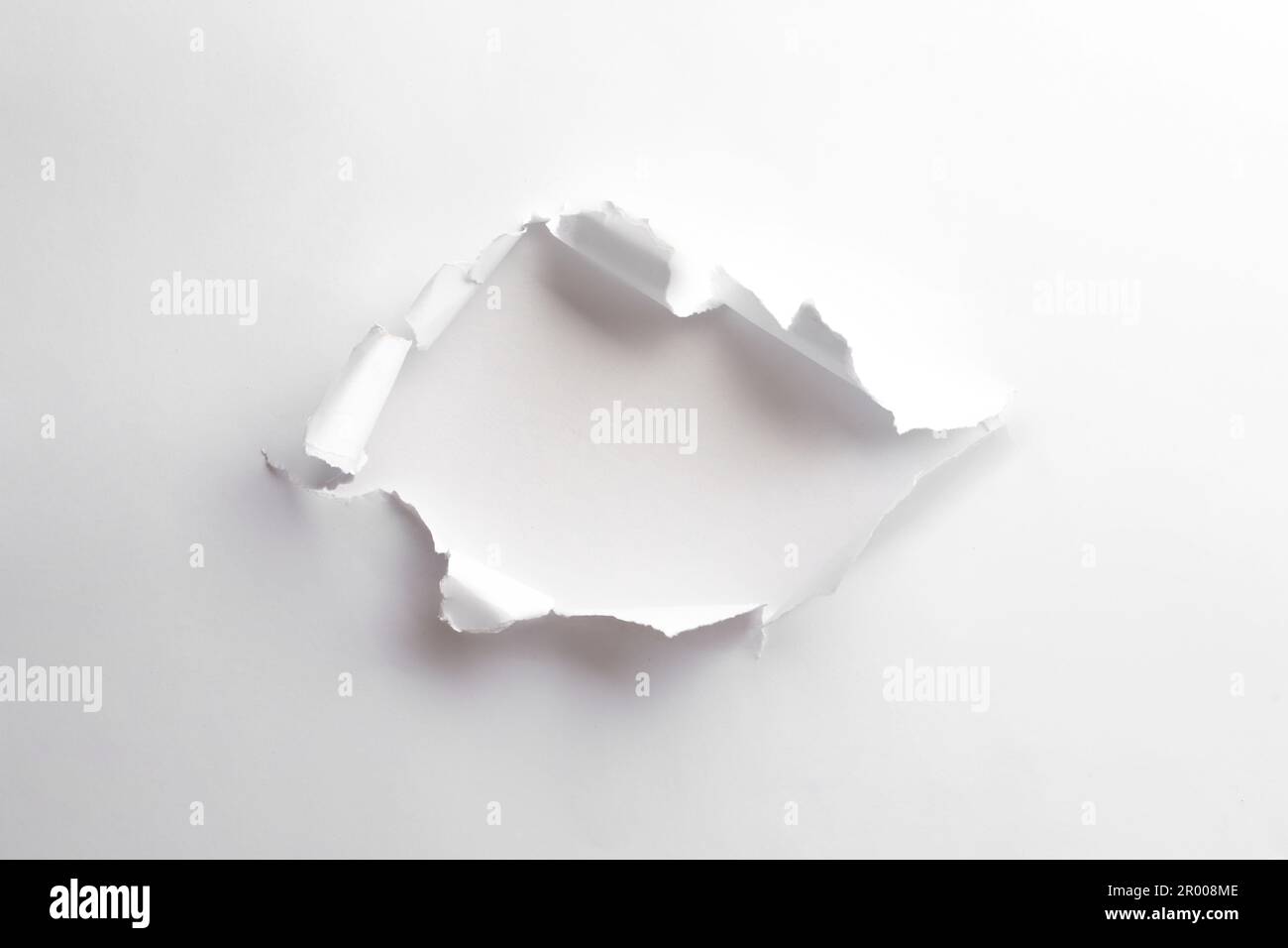 Hole in white paper on light background Stock Photo - Alamy