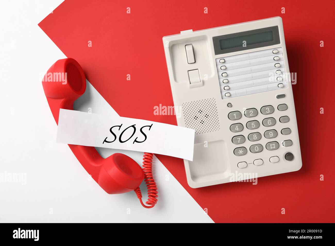 Telephone and paper note with abbreviation SOS on color background ...