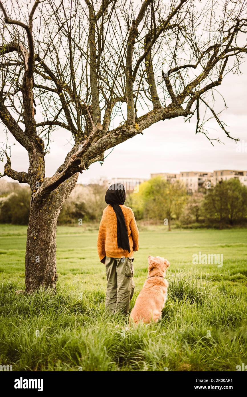 muslim girl standing peaceful with a dog, two best friends under a tree ...