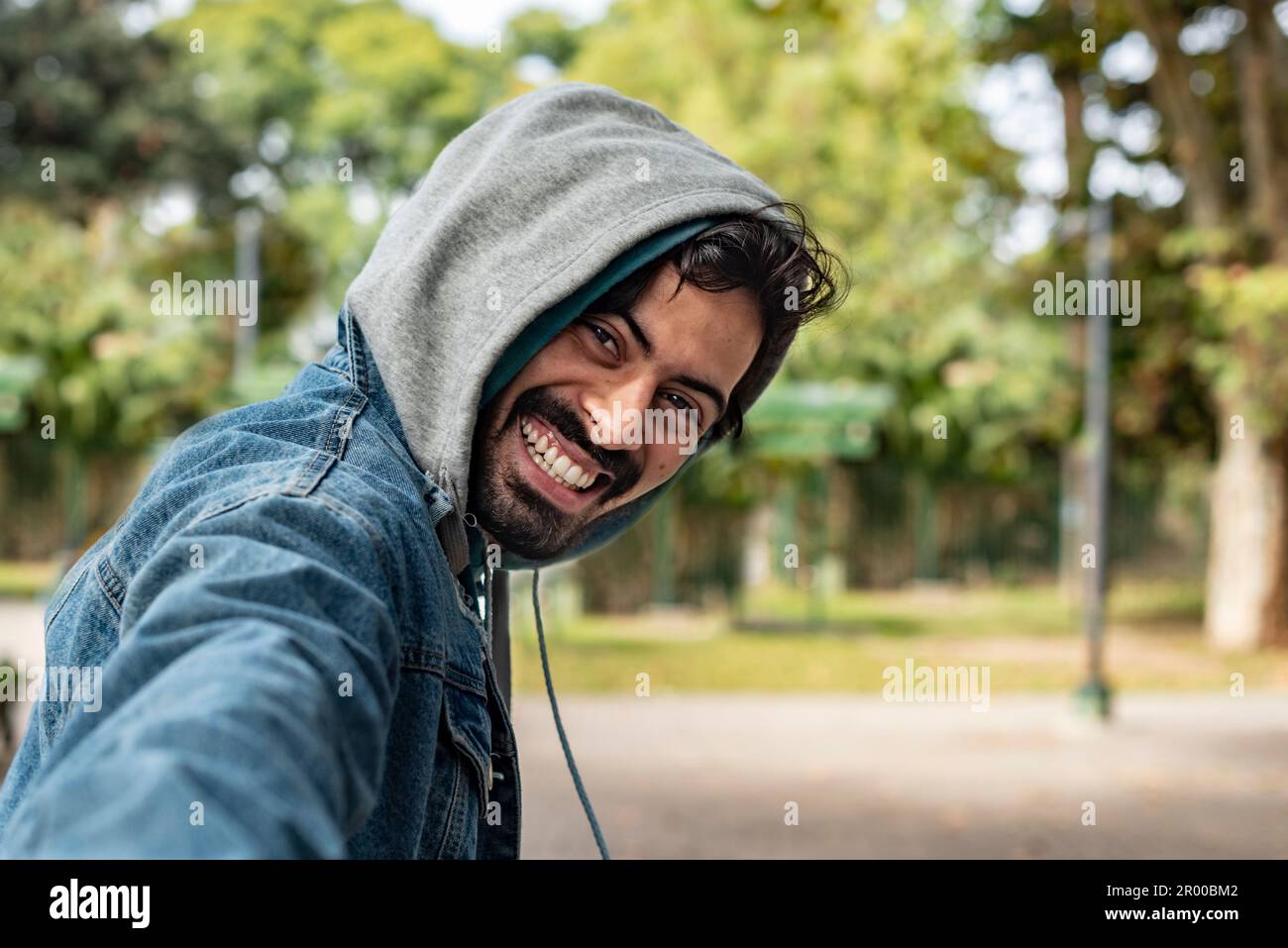 Follow me concept. A smiling young man walking outdoors holding his ...