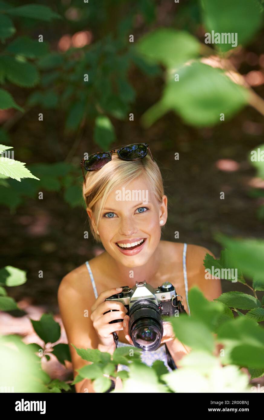 The perfect leafy frame. an attractive young woman taking photographs ...
