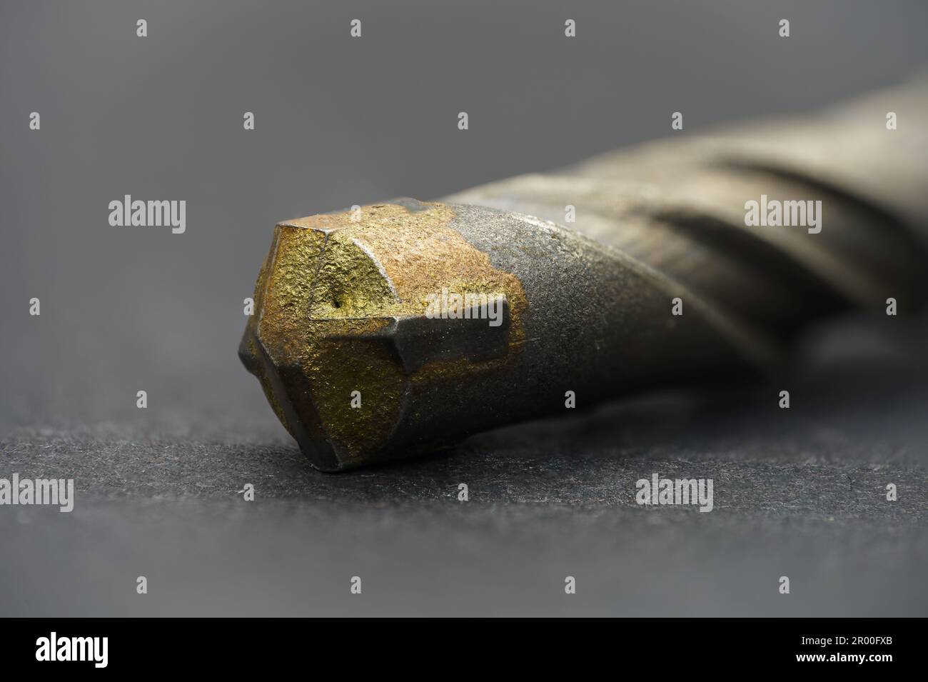 Golden head of concrete drill bit on grey surface. Extreme close up ...