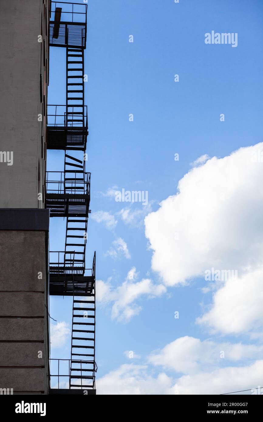 Silhouette of a fire escape on a high-rise building against a blue sky ...