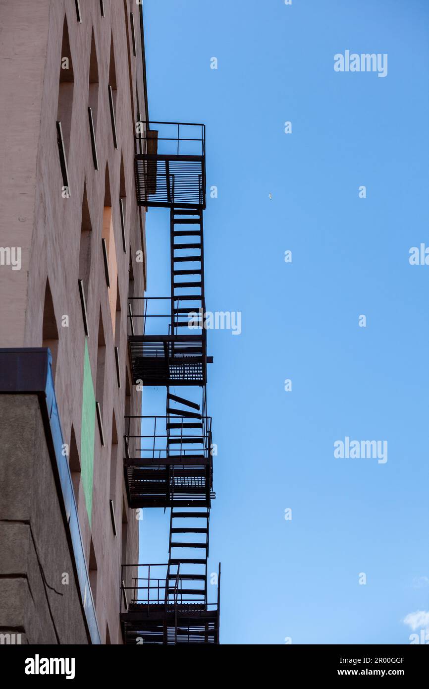 Silhouette of a fire escape on a high-rise building against a blue sky ...
