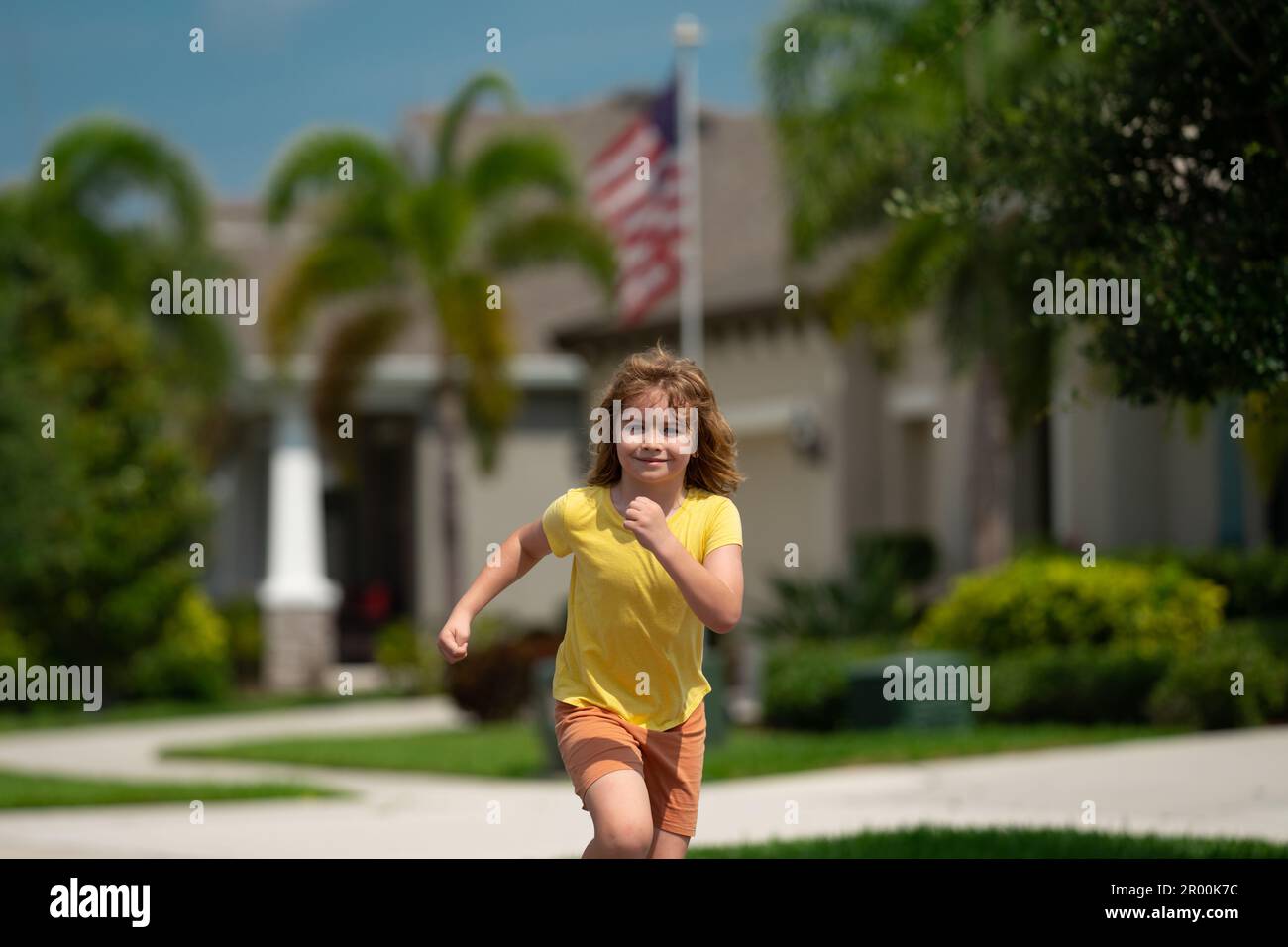 Cute kid boy running across american neighborhood street. Summer ...