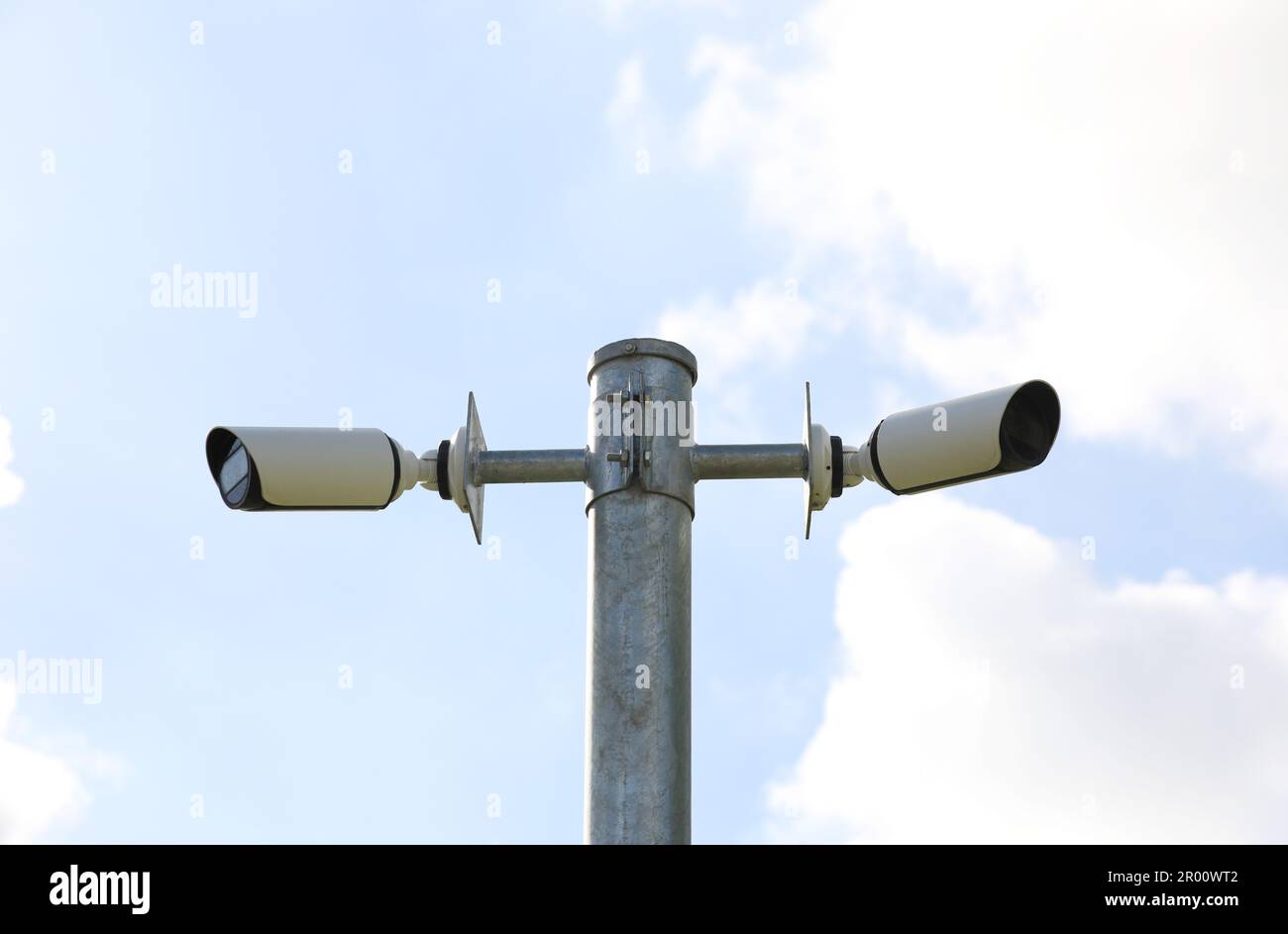 Public surveillance cameras mounted on a post with blue sky background ...