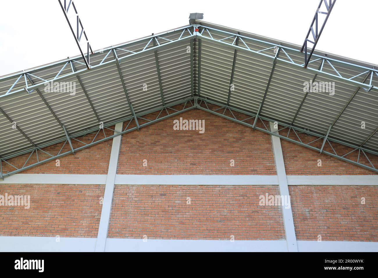 Warehouse roofing built on brick wall facade Stock Photo - Alamy