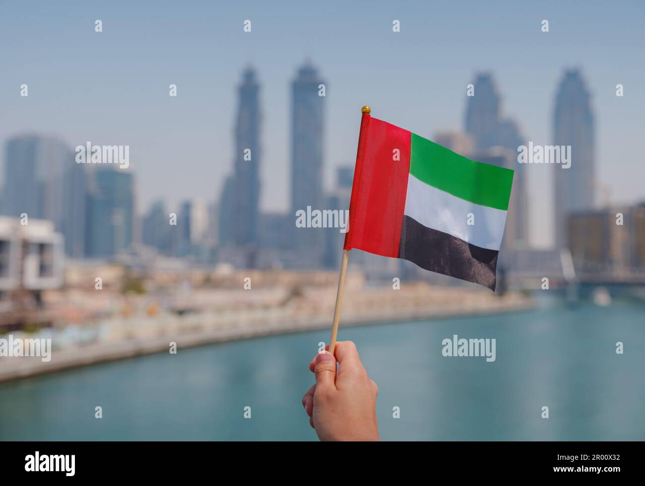 Close up of a female hand holding tiny flag of UAE against Dubai ...