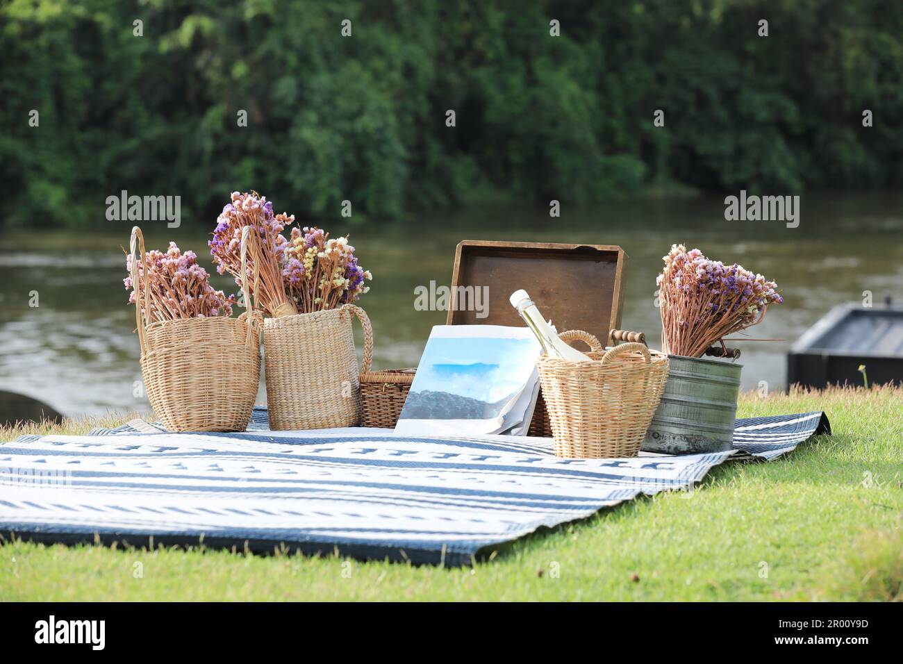 Book and flowers baskets on blue mat with river and forest in ...