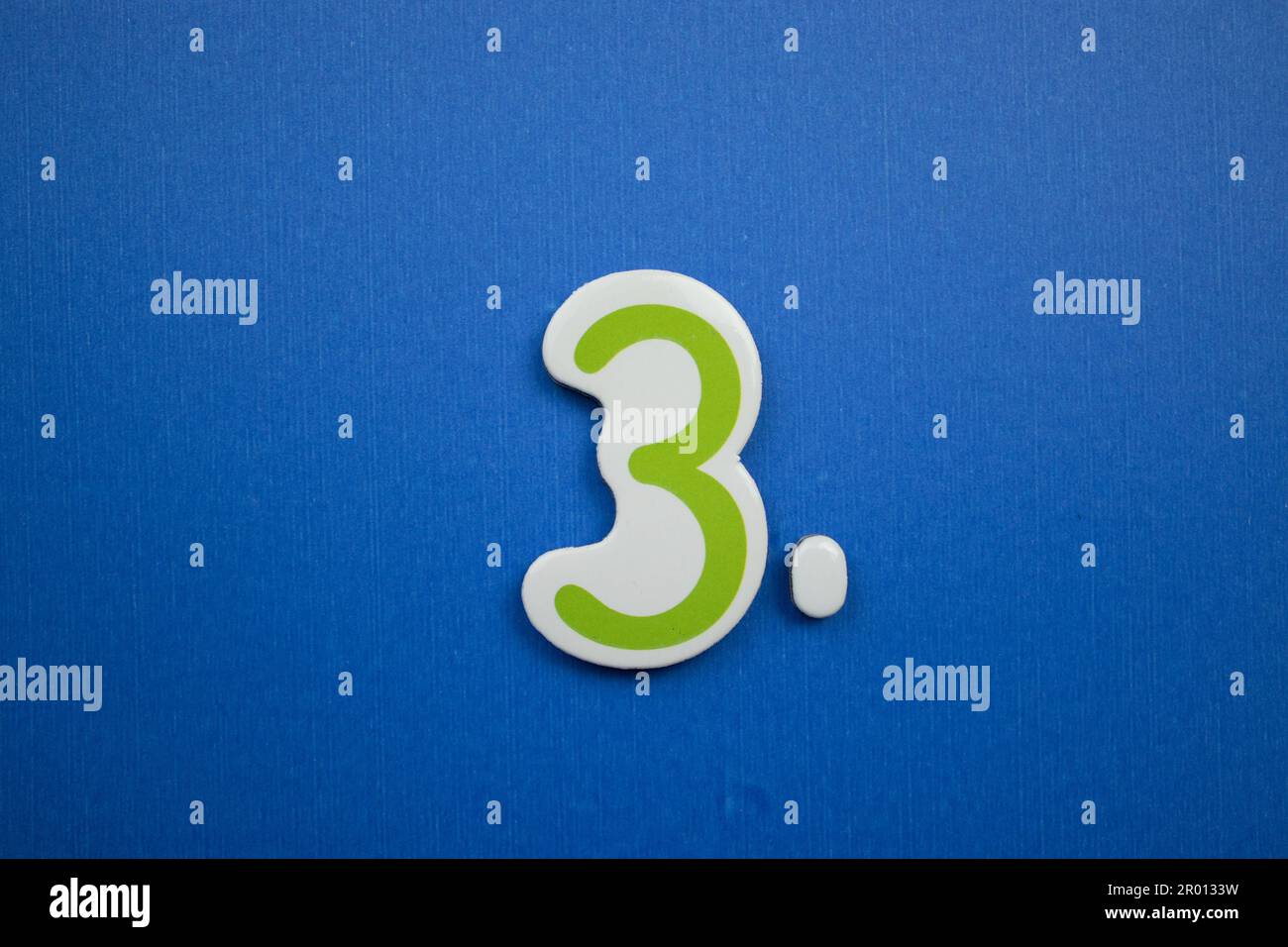 The number 3, placed on a blue background, photographed from above ...