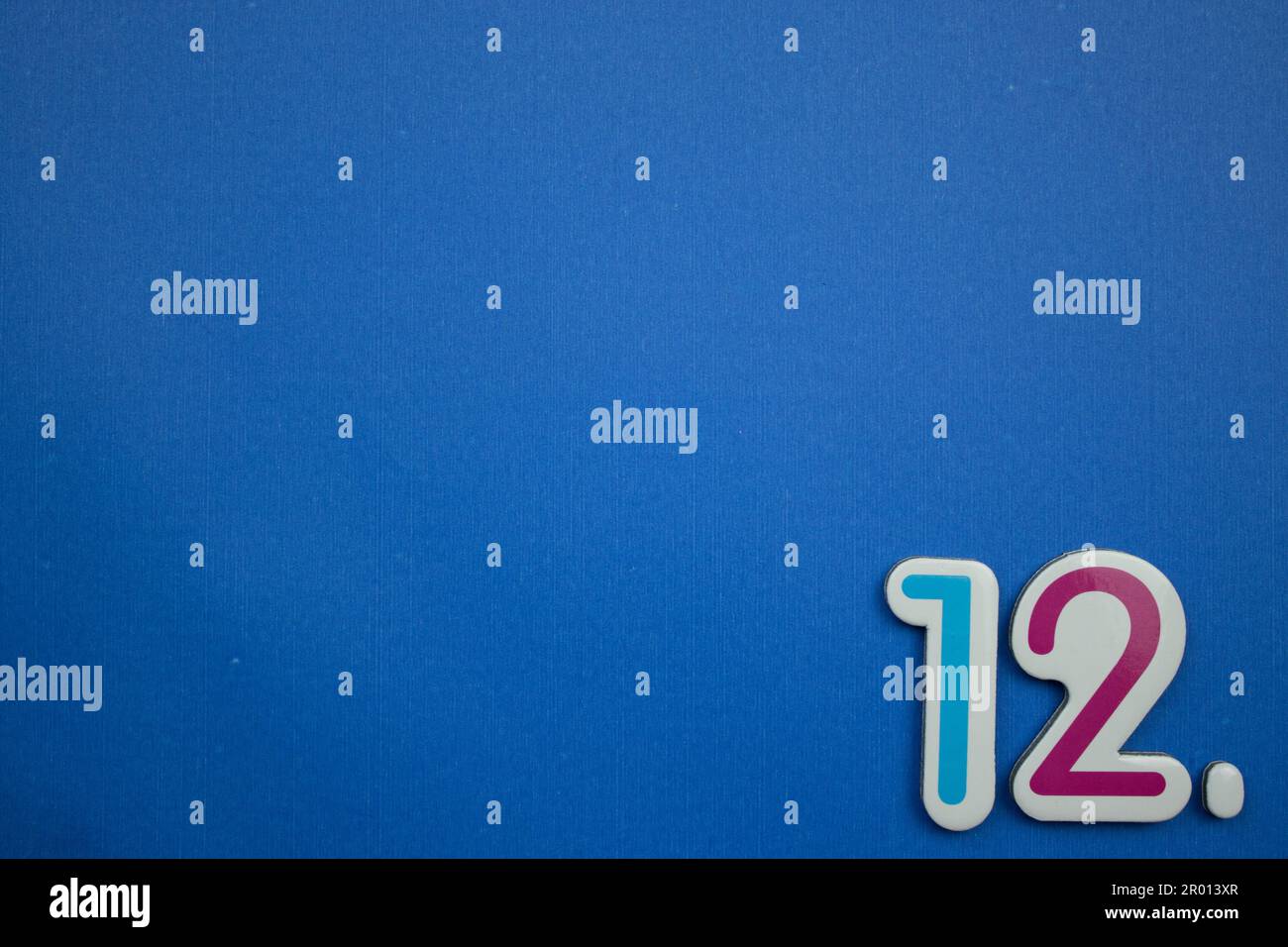 The number 12, placed on the edge of a blue background, photographed ...