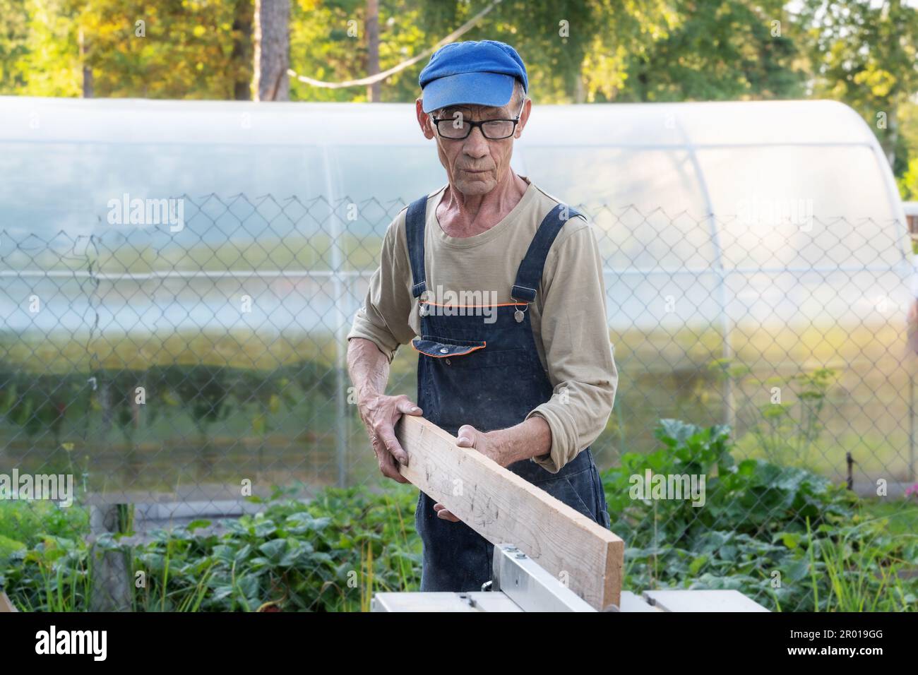 a carpenter processes wooden planks while on the street on a country ...