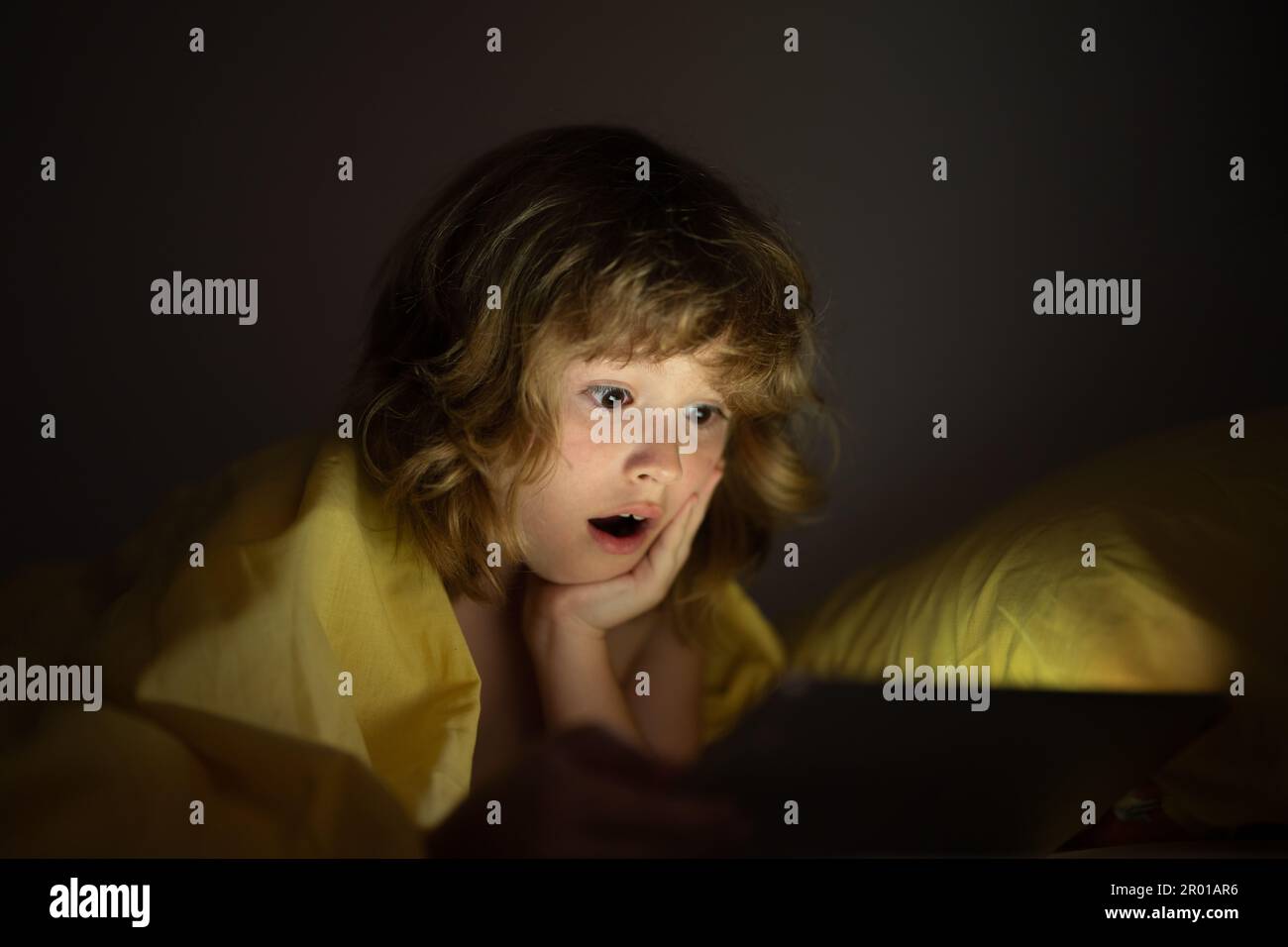 Kid watching tablet before sleeping. Child reads the e-book. Little boy ...