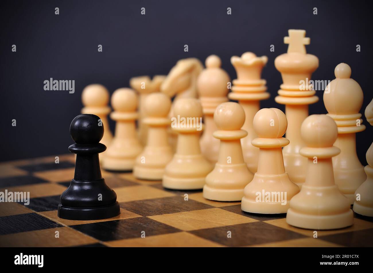 Black chess pawn standing in front of white chess pieces Stock Photo ...