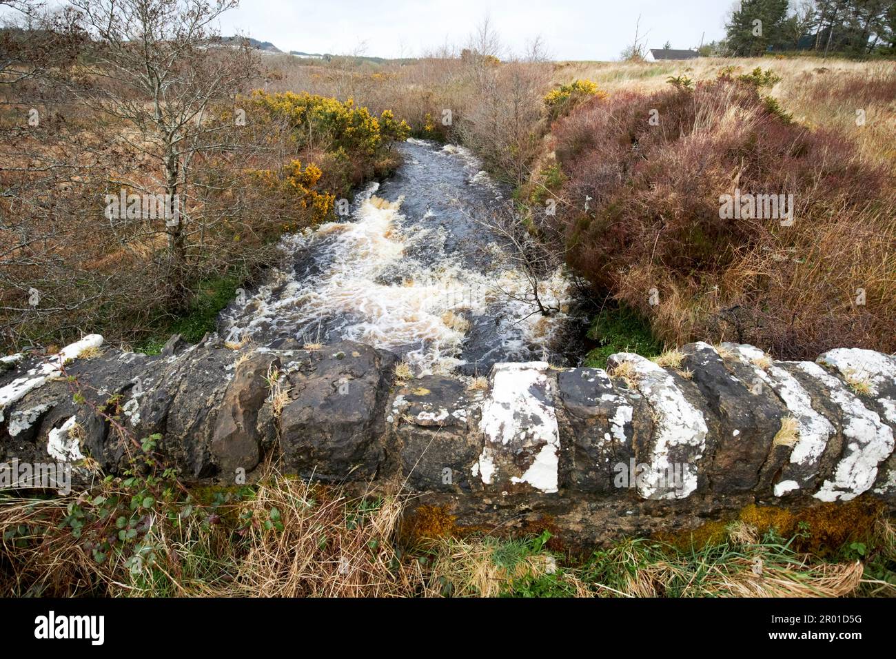 old stone bridge over small stream river in flood in remote rural ...