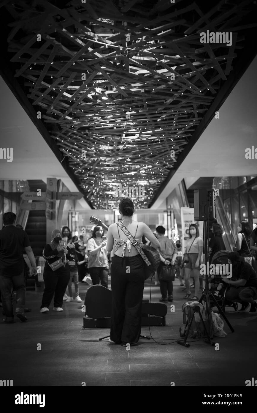 A woman playing the guitar in a crowded building in grayscale Stock ...