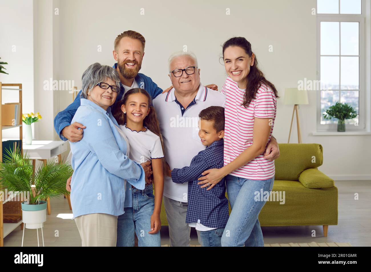 Happy children, parents and grandparents standing in the living room ...