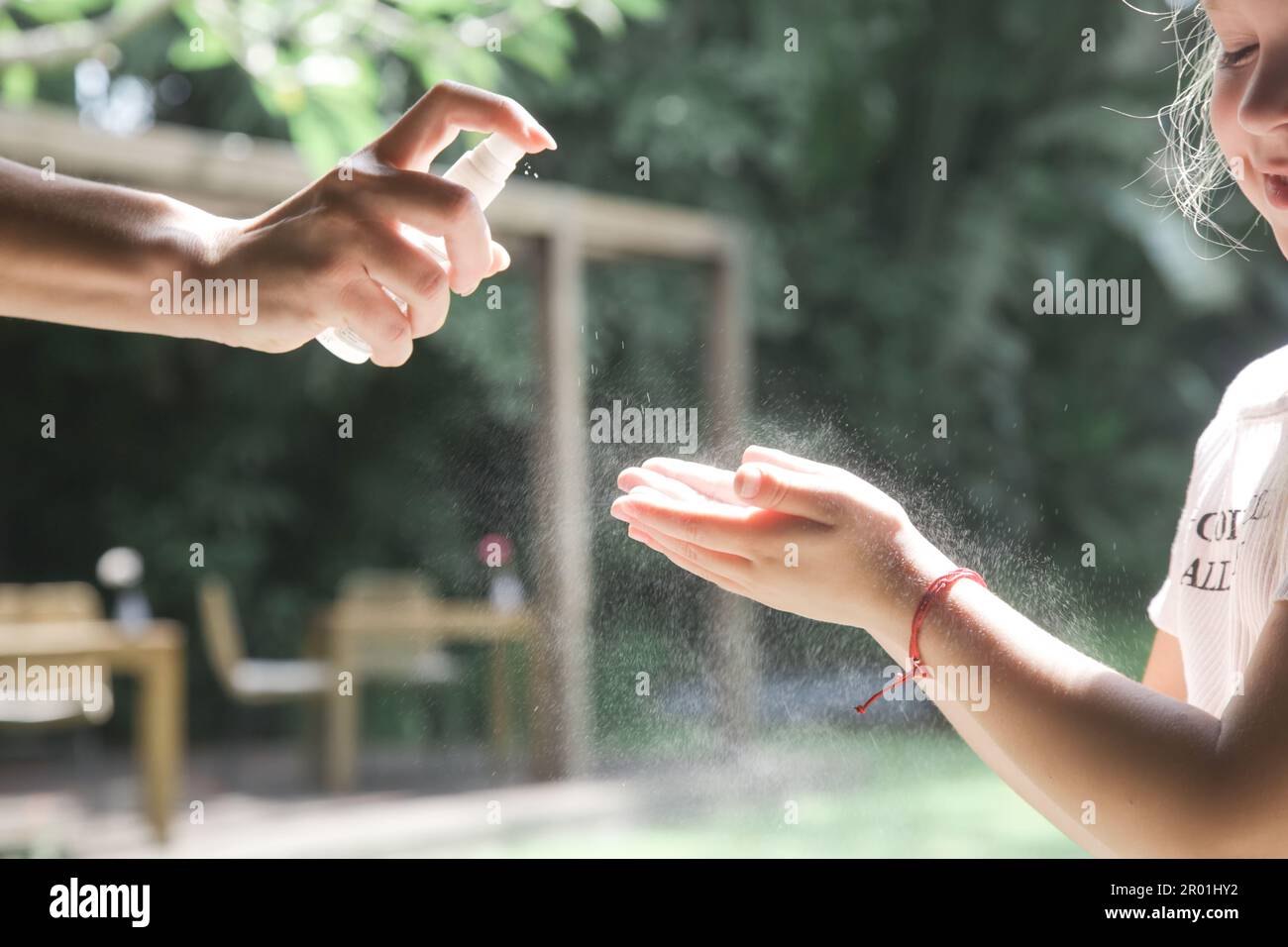 Mother applying hand sanitizer or mosquito repellent spray on her child ...