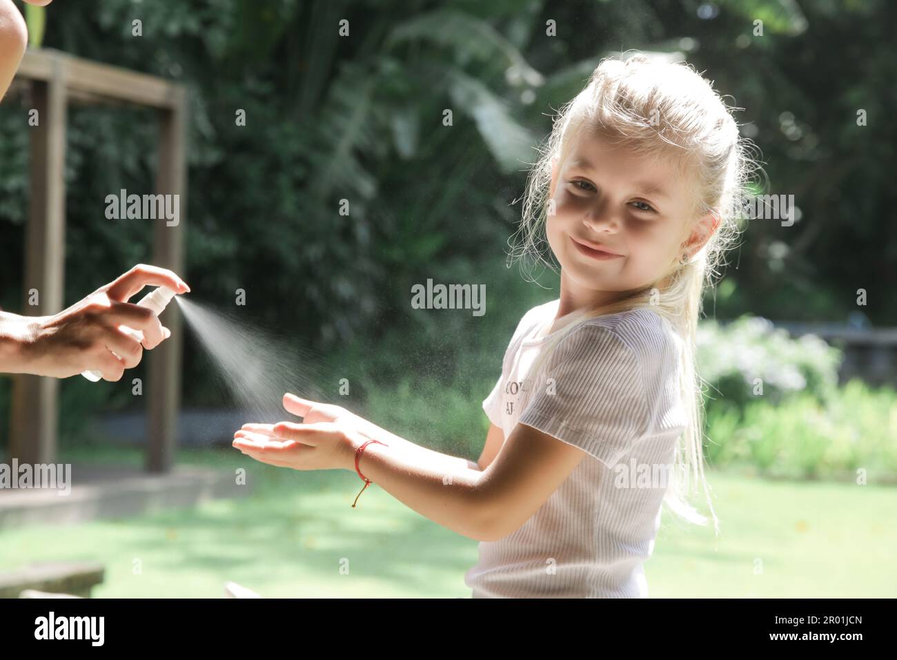 Mother applying hand sanitizer or mosquito repellent spray on her child ...