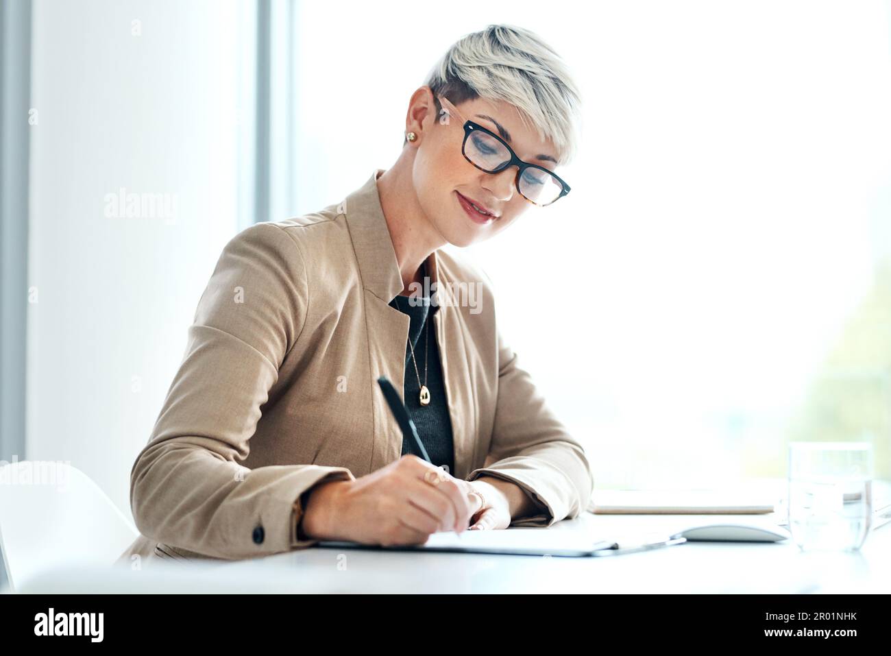 Jotting down a few things. a young businesswoman writing notes in an ...