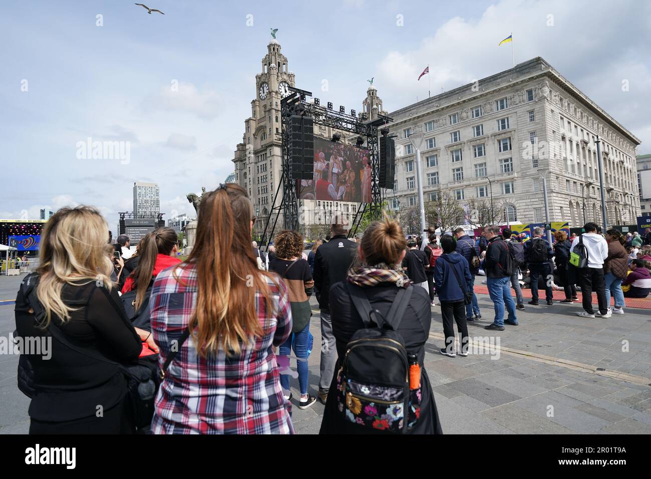 Members of the public watch the coronation of King Charles III and Queen Camilla on a big screen ...