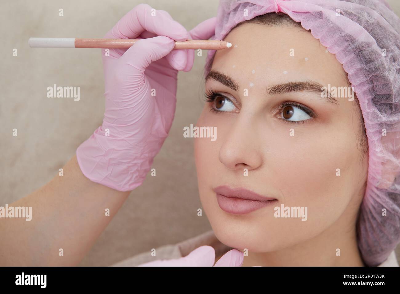 Cosmetologist drawing mark on client face to prepare for rejuvenation ...