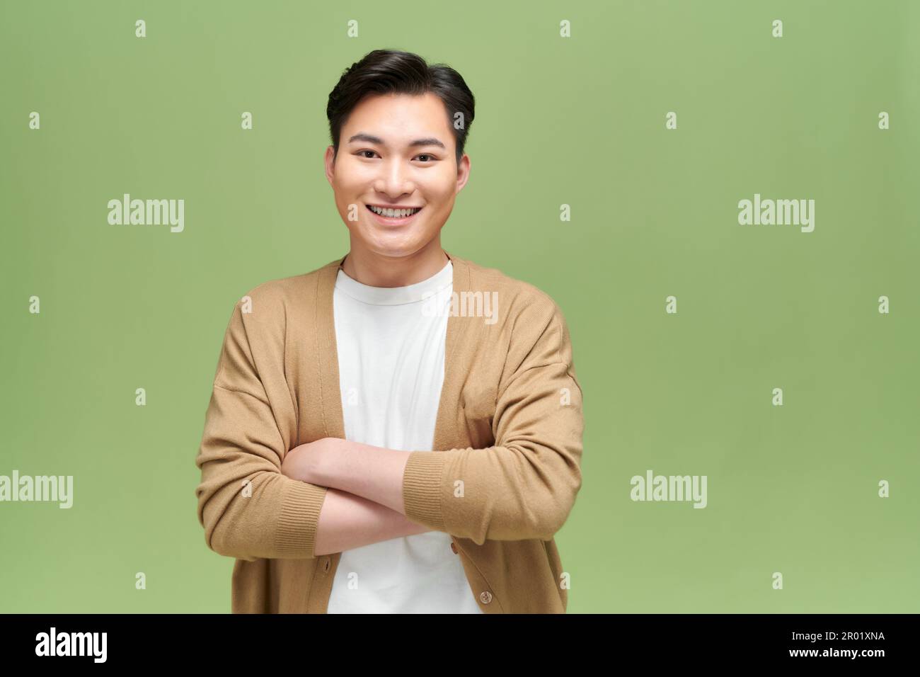 Positive asian man standing on isolated background with hands crossed ...