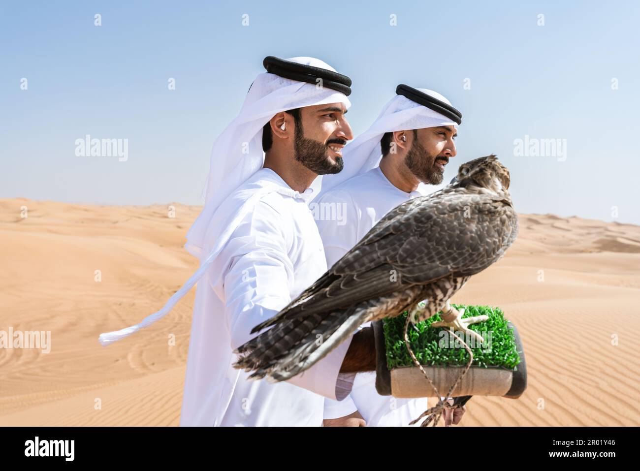 Two middle-eastern men wearing traditional emirati arab kandura bonding ...