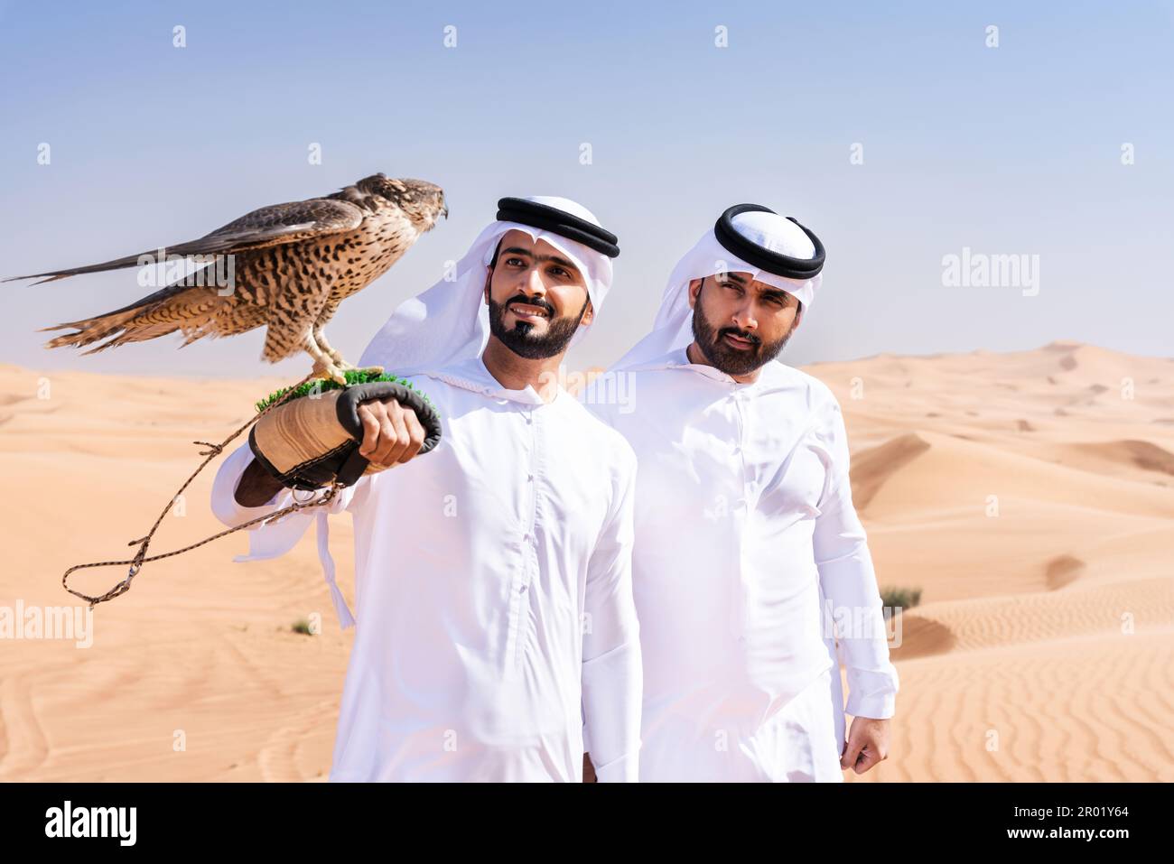 Two middle-eastern men wearing traditional emirati arab kandura bonding ...