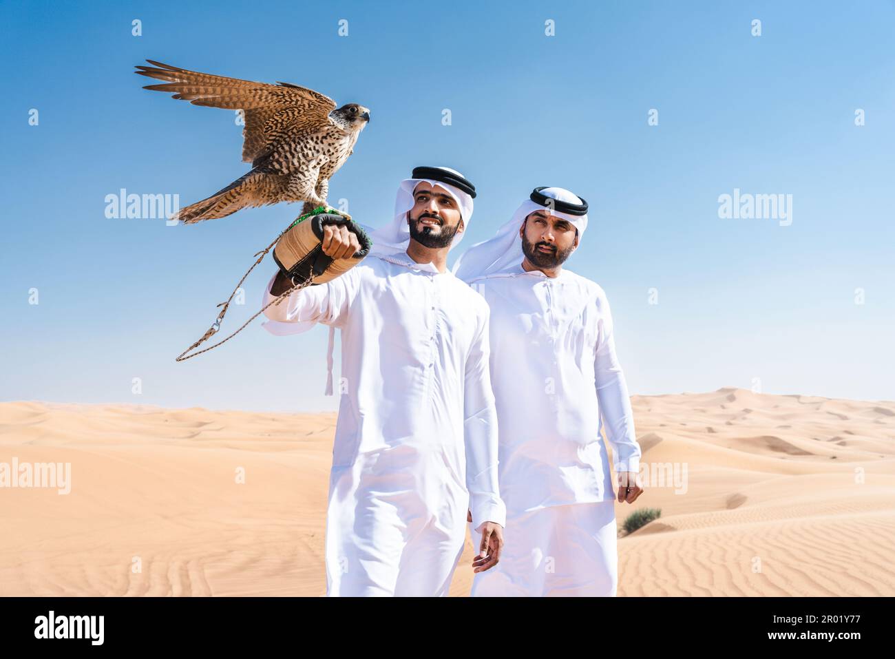 Two middle-eastern men wearing traditional emirati arab kandura bonding ...