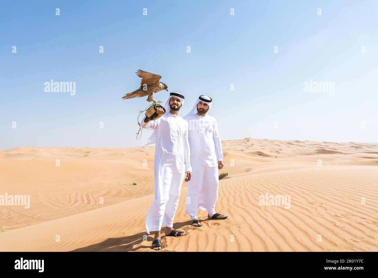 Two middle-eastern men wearing traditional emirati arab kandura bonding ...