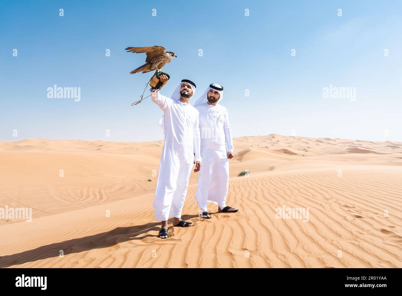 Two middle-eastern men wearing traditional emirati arab kandura bonding ...