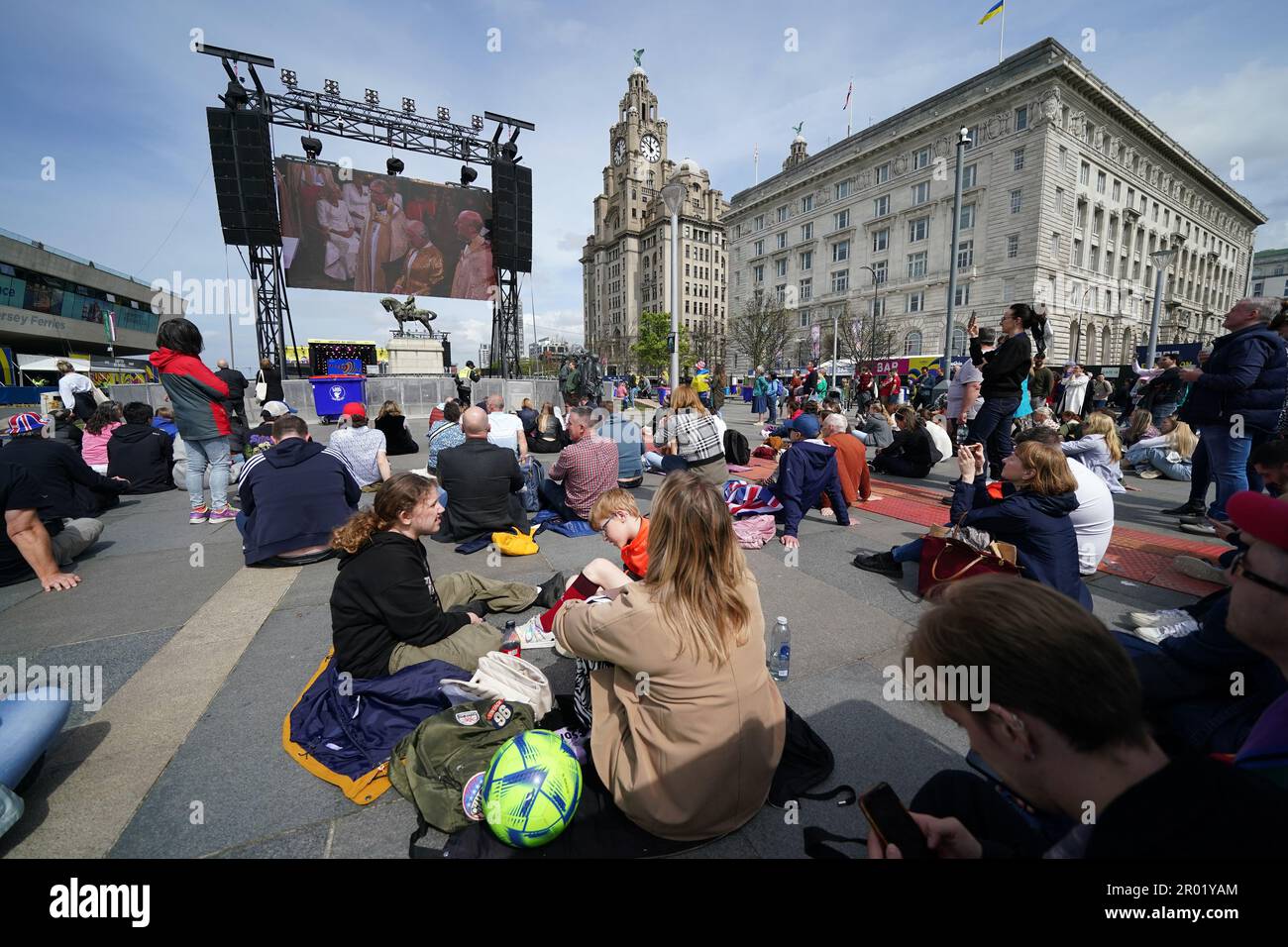 Members of the public watch the coronation of King Charles III and Queen Camilla on a big screen ...