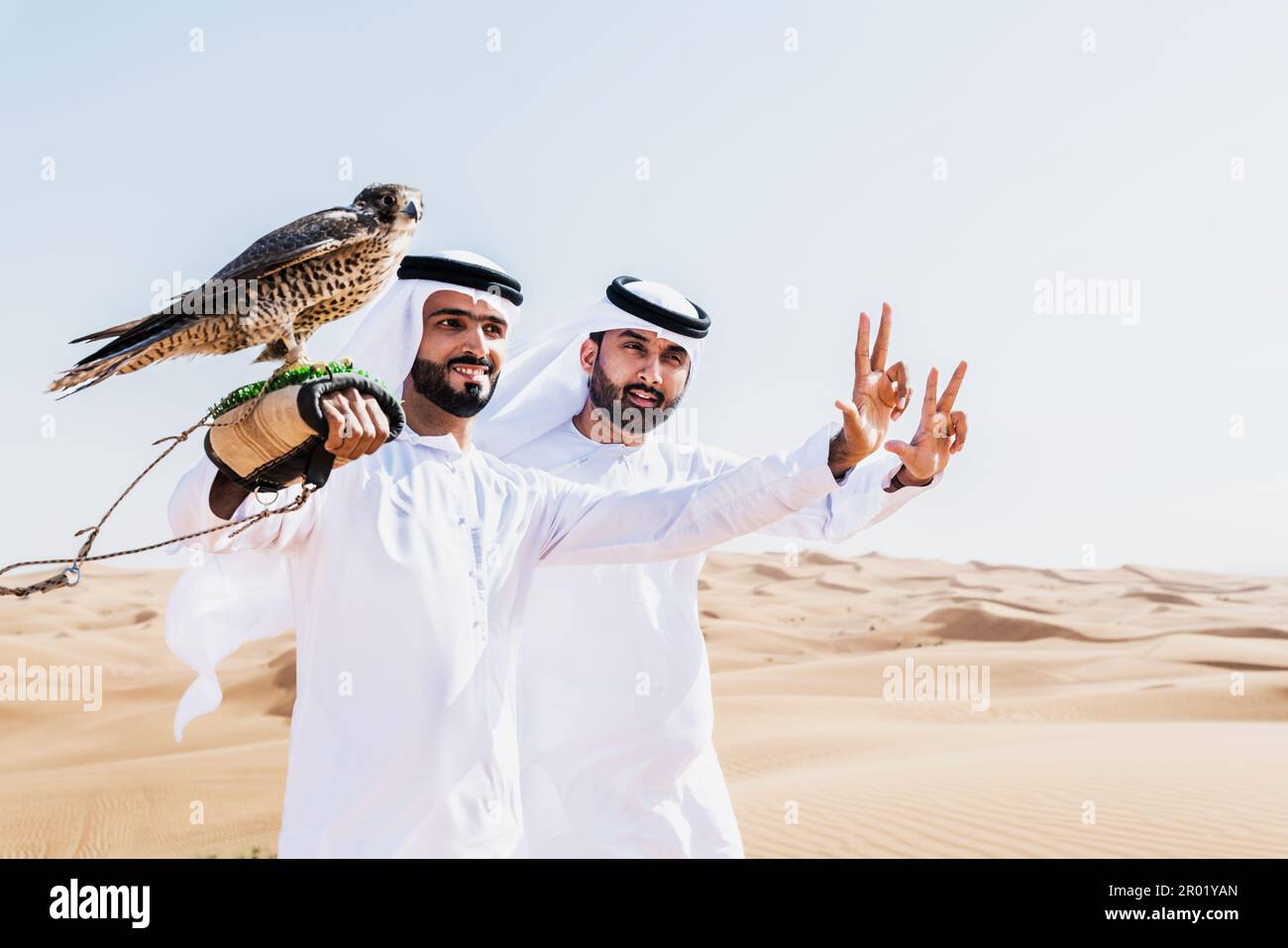 Two middle-eastern men wearing traditional emirati arab kandura bonding ...