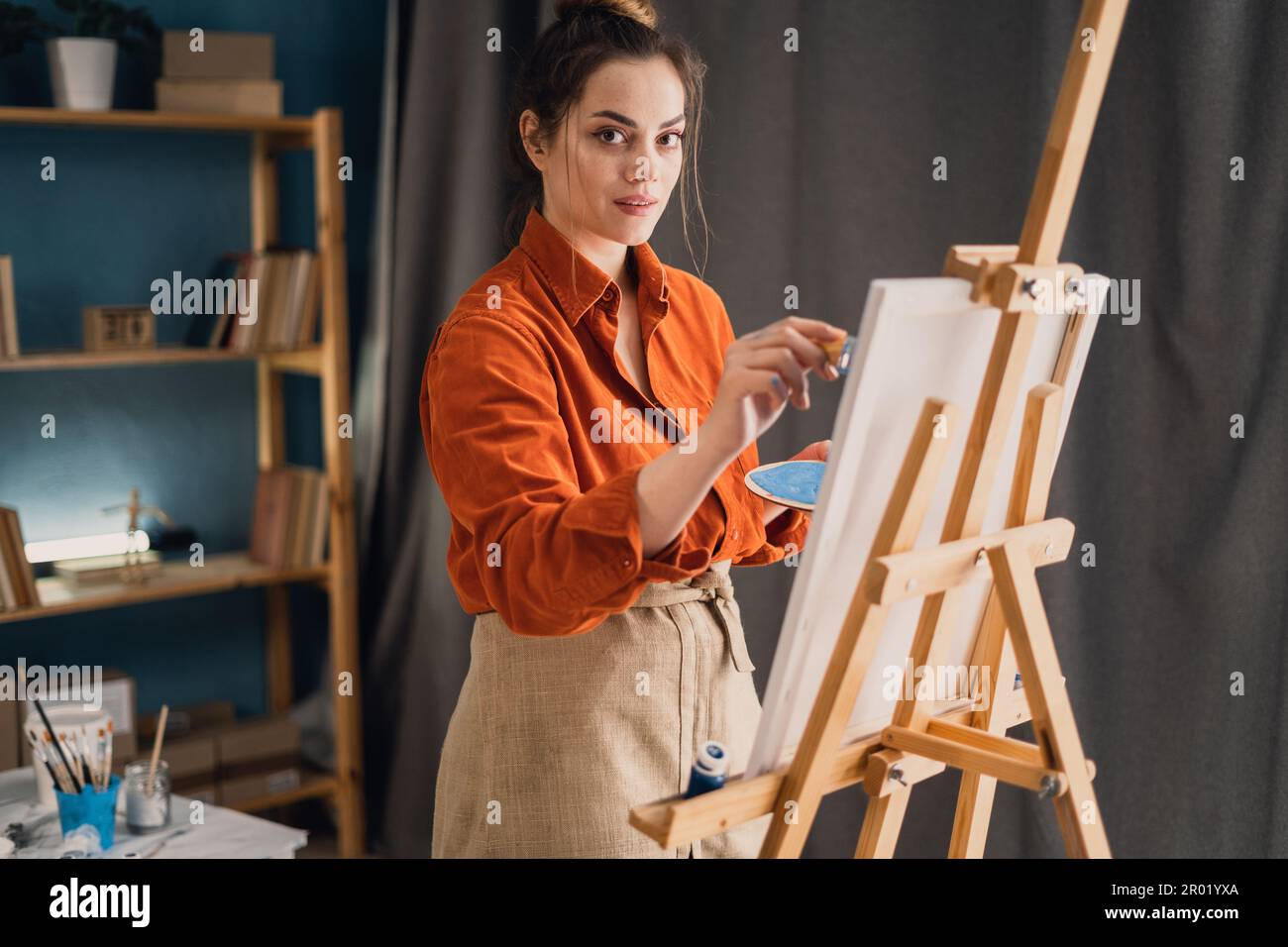 Creative latin female artist standing working on a new painting. Happy ...