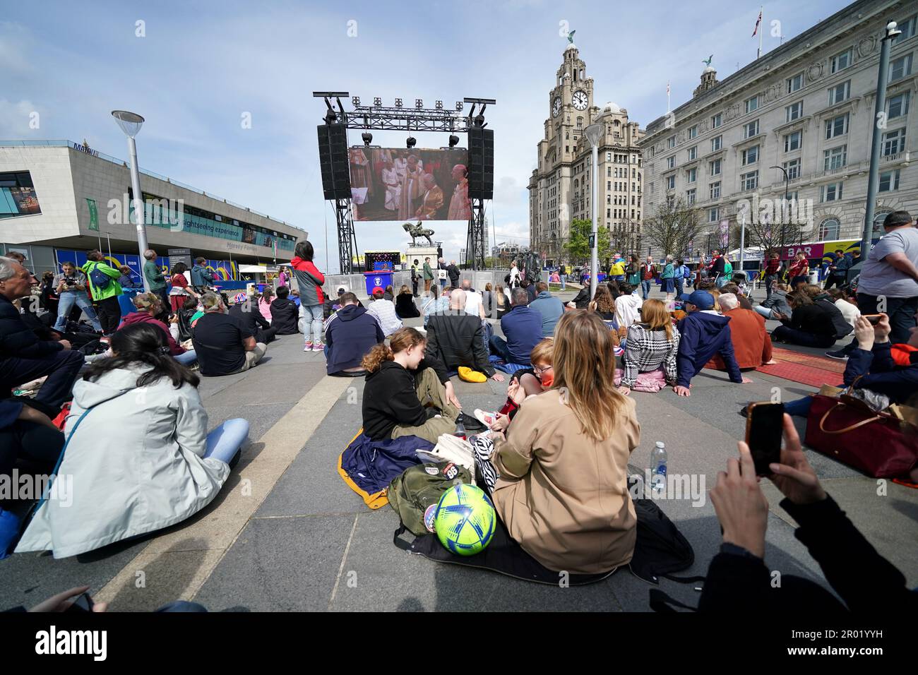 Members of the public watch the coronation of King Charles III and Queen Camilla on a big screen ...