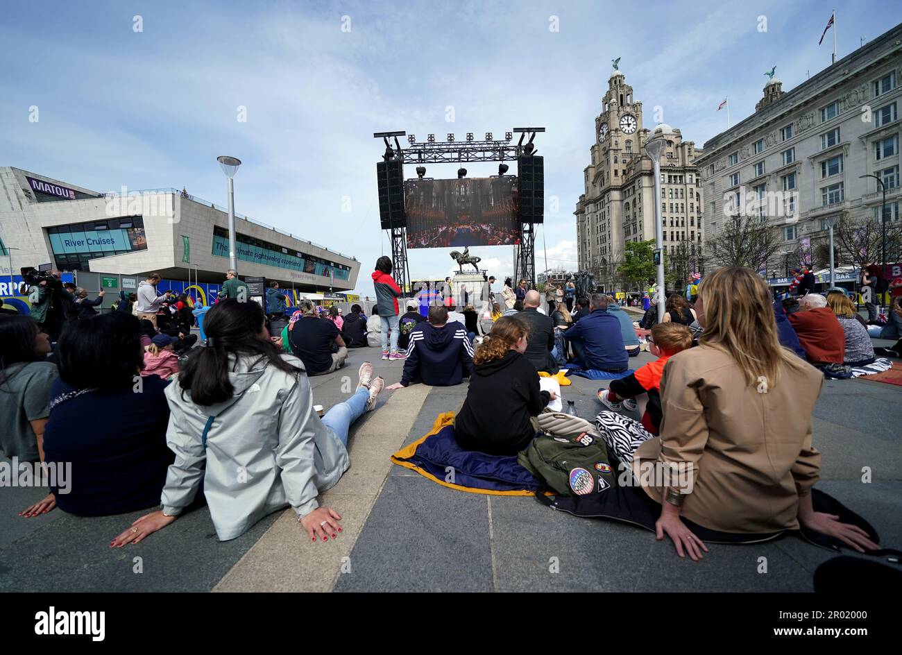 Members of the public watch the coronation of King Charles III and Queen Camilla on a big screen ...