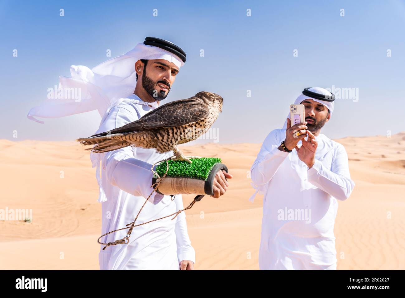 Two middle-eastern men wearing traditional emirati arab kandura bonding ...