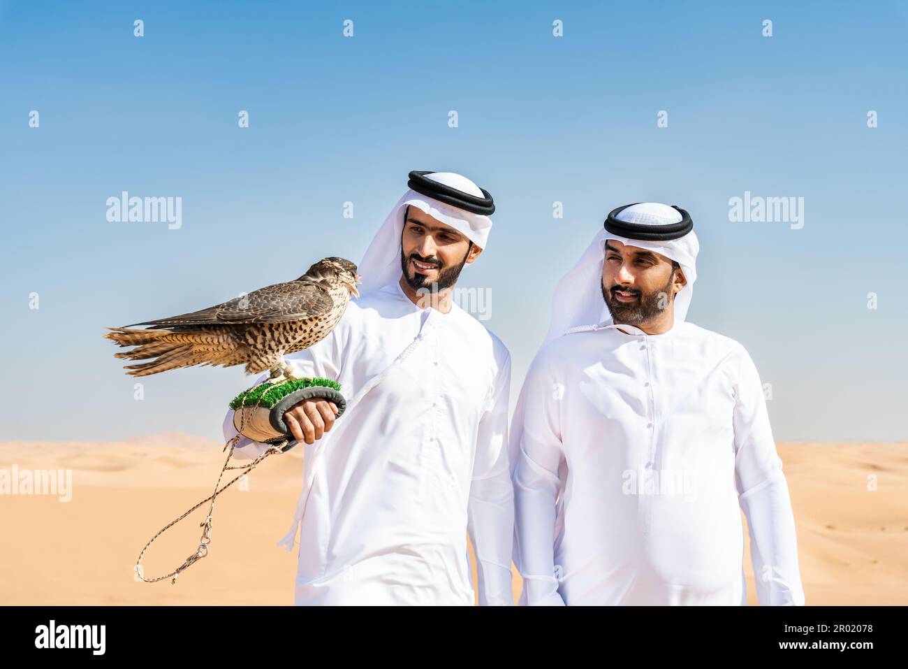 Two middle-eastern men wearing traditional emirati arab kandura bonding ...