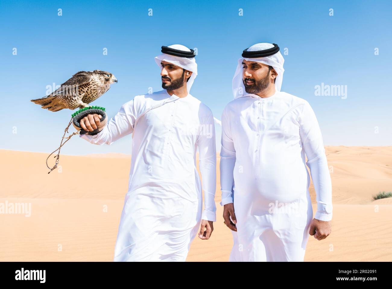 Two middle-eastern men wearing traditional emirati arab kandura bonding ...