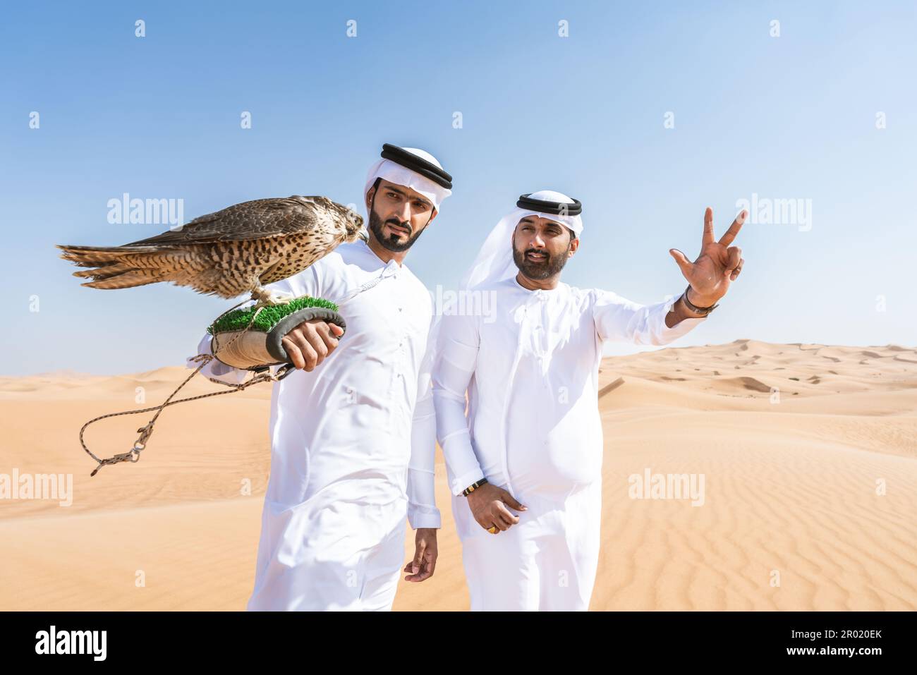 Two middle-eastern men wearing traditional emirati arab kandura bonding ...