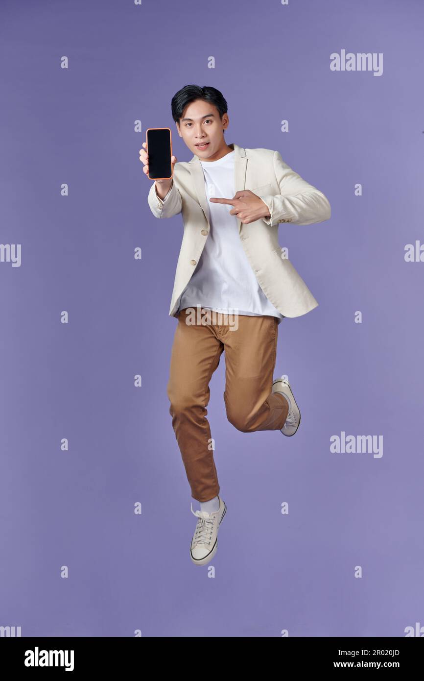 Excited young man guy jumping point index finger on mobile phone with ...